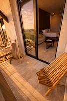Quarto moderno com uma grande porta de vidro para uma varanda, um banco de madeira e um sofá com uma mesa de centro.