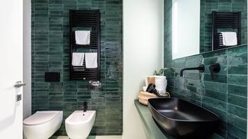 Uma casa de banho moderna com bidé, sanita e lavatório preto.