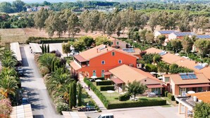 Zona residencial com casas equipadas com painéis solares, uma rua com carros estacionados e muita vegetação.