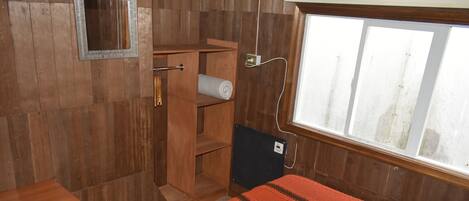 Quarto de madeira com cama, escrivaninha, armário e janela.