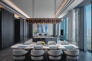 Uma sala de conferências moderna com uma mesa comprida, cadeiras brancas e vista para a cidade.