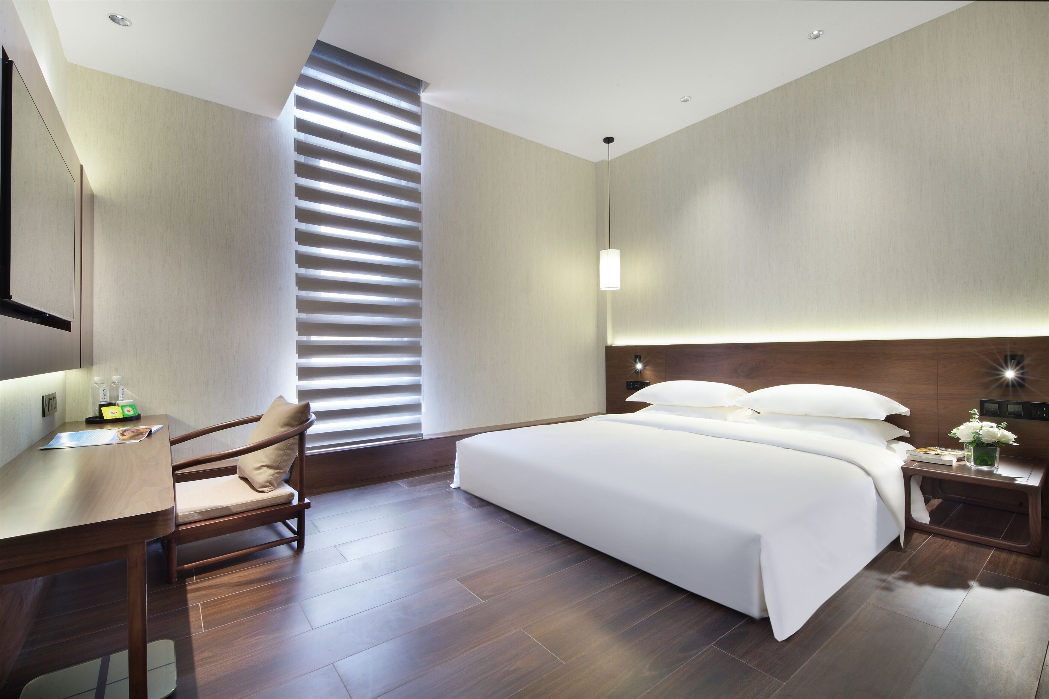 Quarto de hotel moderno com uma cama grande, uma mesa e uma cadeira.