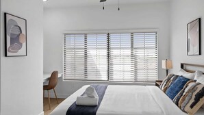 Quarto de hotel com cama, escrivaninha e cadeira.