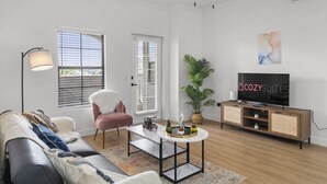 Uma sala de estar moderna com sofá, mesa de centro, televisão e ventoinha de teto.