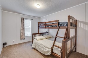 Quarto com beliche, luz no teto, janela com cortinas e piso coberto por carpete.