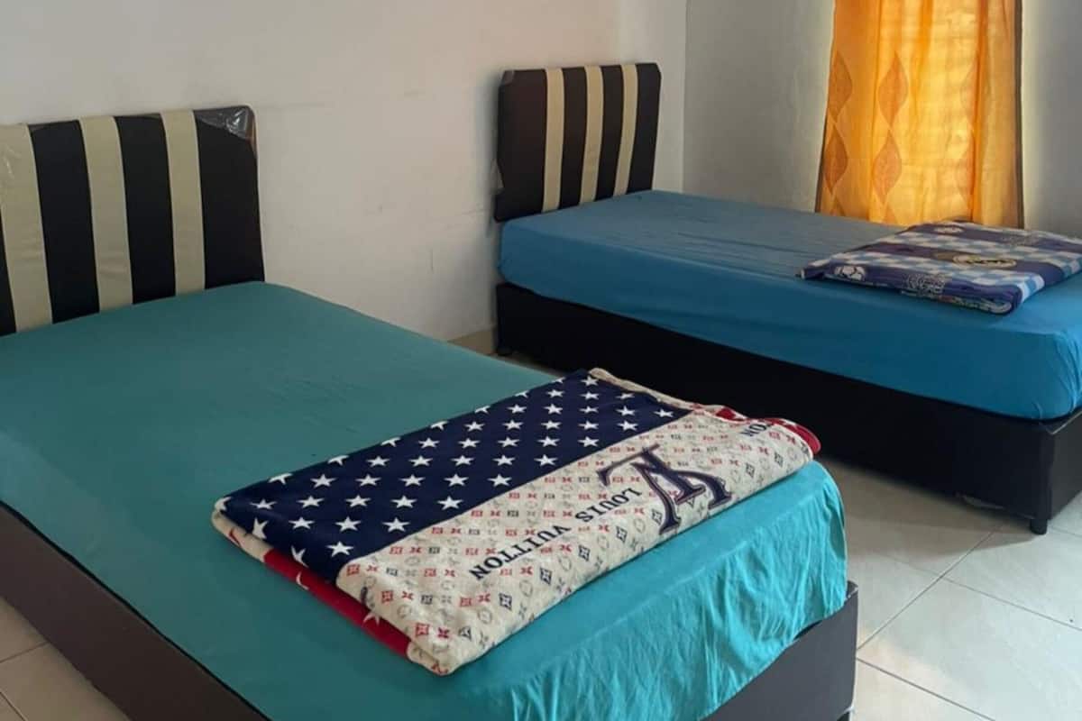 Quarto com duas camas, uma com colcha azul e a outra com colcha azul e branca listrada.