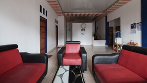 Sala de estar com dois sofás vermelhos, uma mesa de centro e teto com listras laranja e branco.