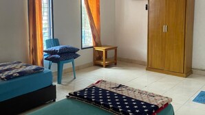 Quarto com cama, guarda-roupa, cadeira e uma mesinha.