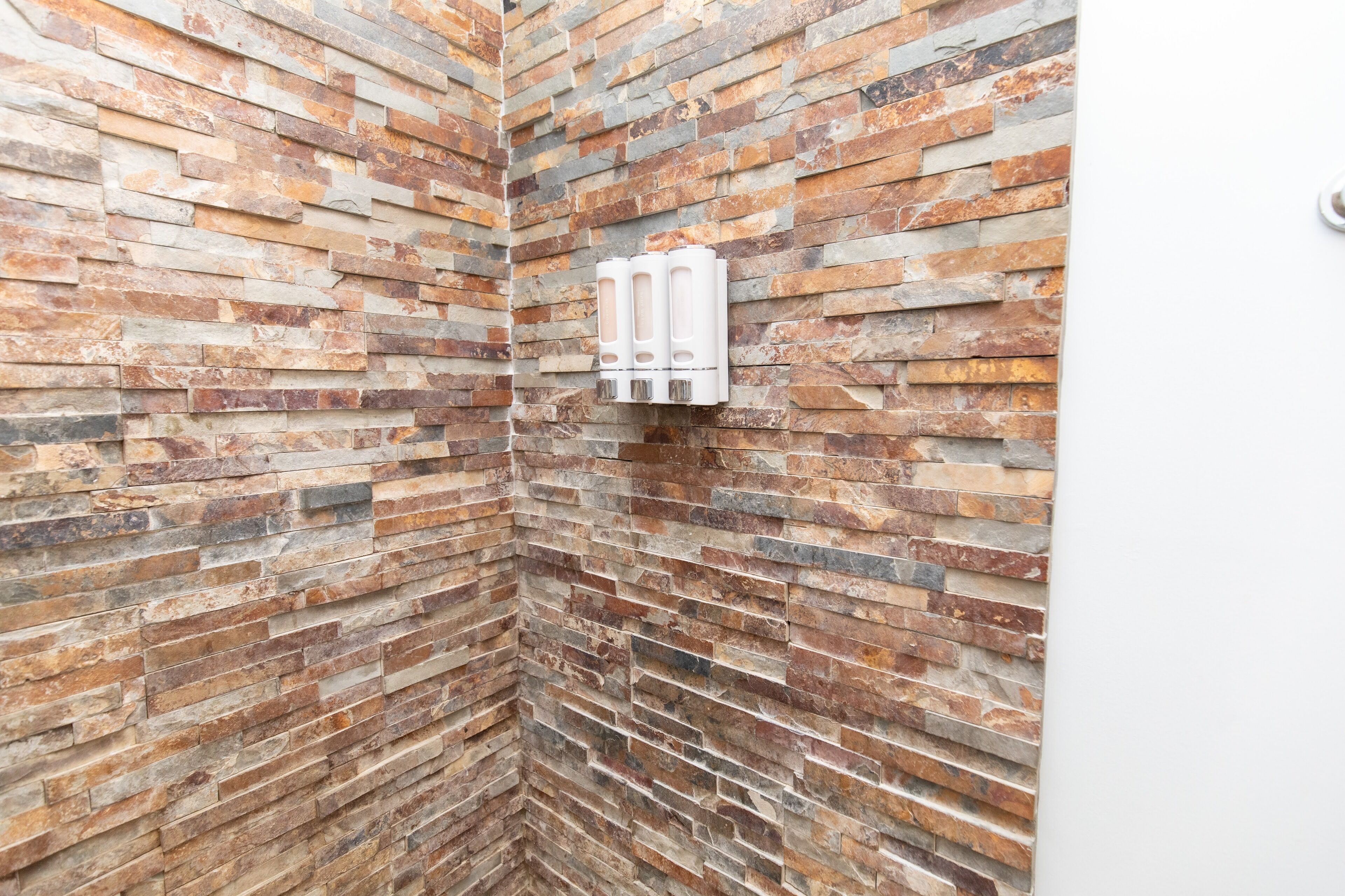 Canto de um quarto com parede de tijolos e um objeto branco fixado nela.