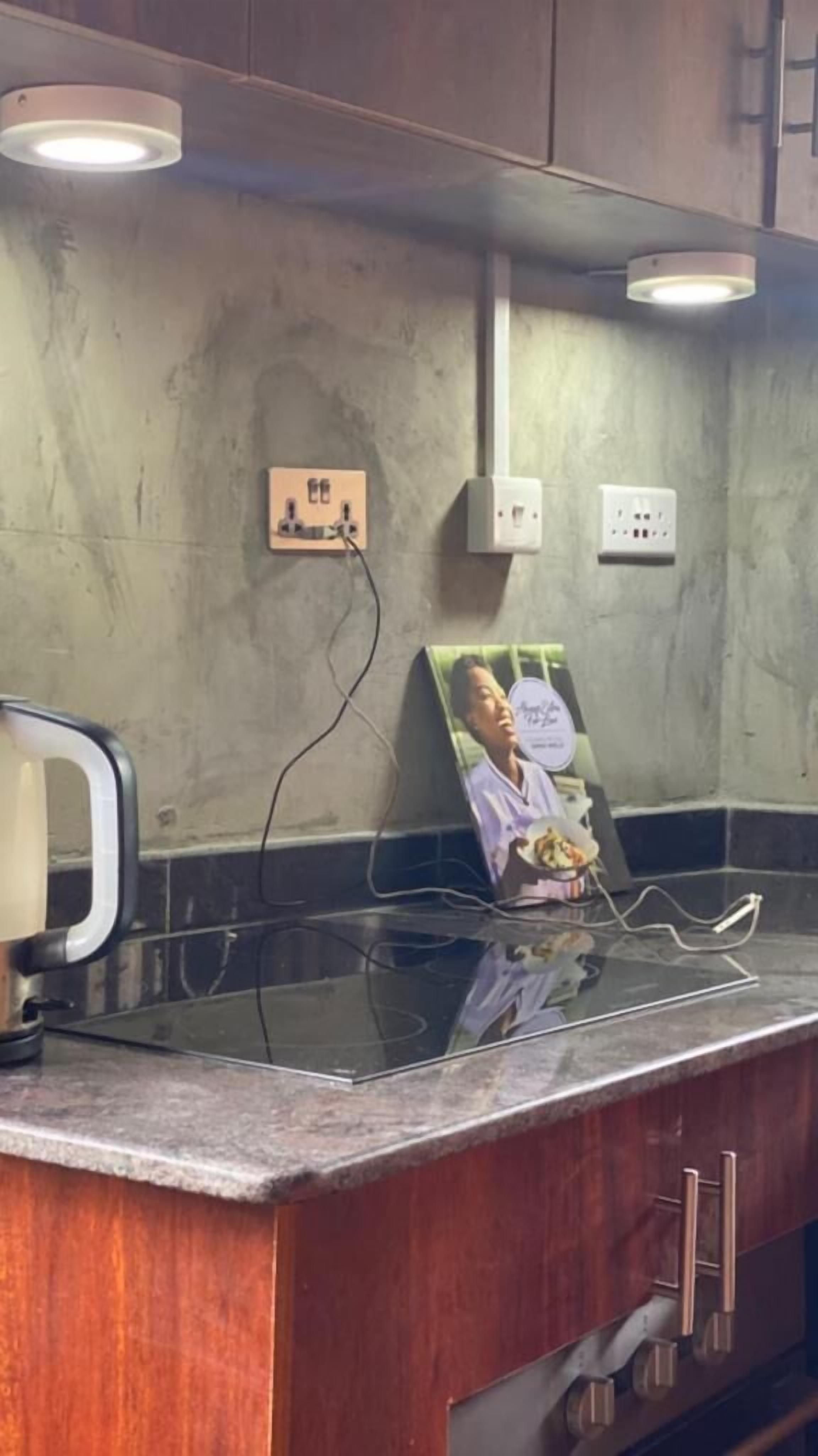 Uma bancada de cozinha com tampo de vidro, uma máquina de café e um cartaz na parede.