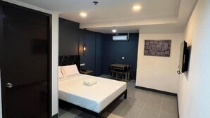 Quarto com cama, mesa de cabeceira e um pequeno espaço para escritório.