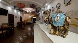 Uma área de recepção com um balcão comprido, piso de madeira e uma escadaria ao fundo.