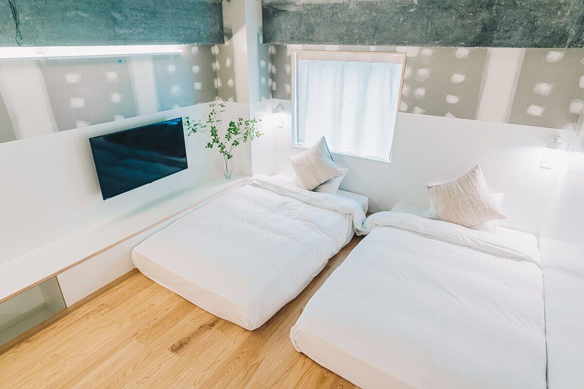Quarto moderno com cama, televisão, janela e planta.