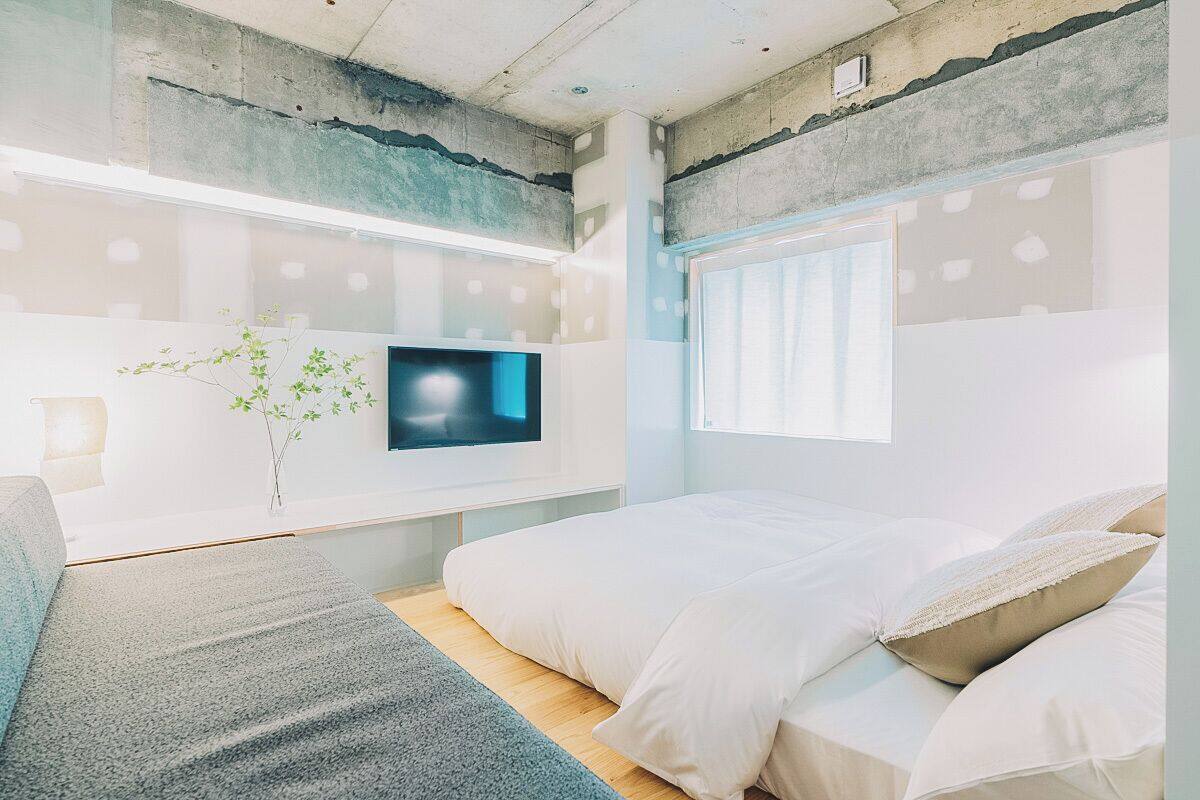 Quarto moderno com uma cama, uma televisão e uma janela.