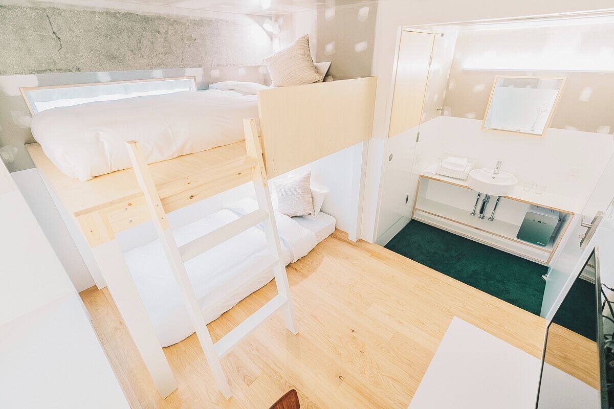 Quarto com beliche e banheiro pequeno, incluindo pia e espelho.