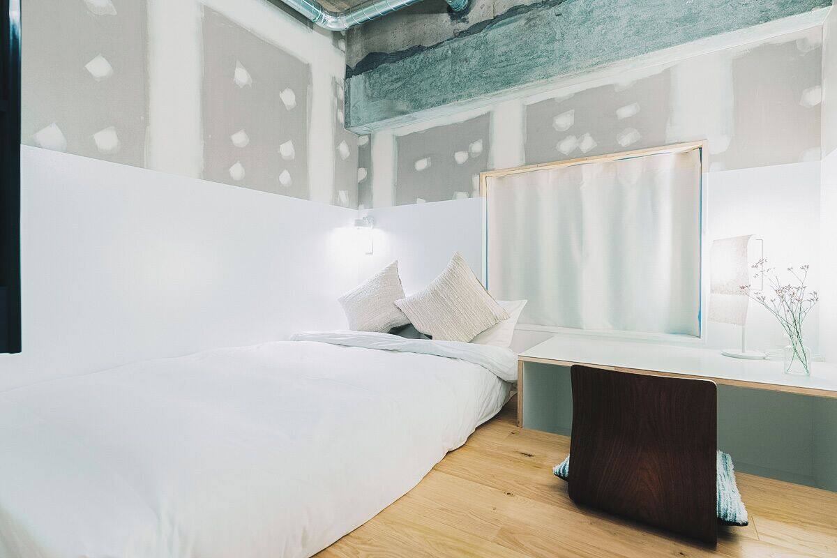 Quarto com cama, mesa de cabeceira e um espelho grande.