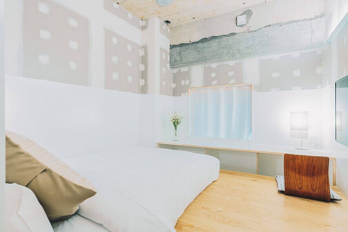 Um quarto com uma cama, uma escrivaninha e uma janela.