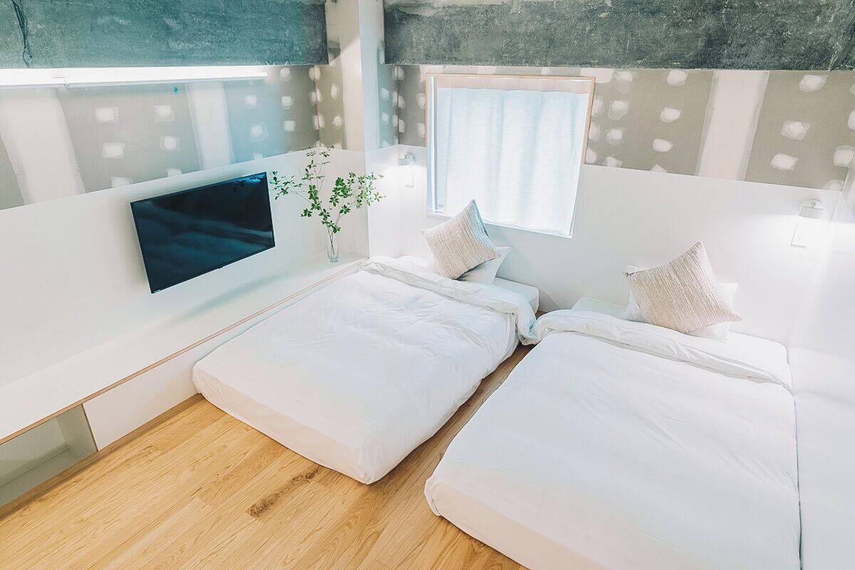 Quarto moderno com cama, televisão e janela.