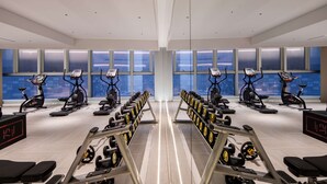 Uma academia com várias esteiras, bicicletas ergométricas e aparelhos de musculação.
