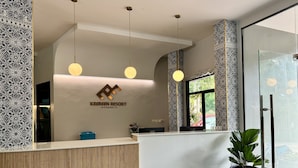 Bancada de recepção no Keerong Resort, com design moderno, incluindo papel de parede estampado, painel de madeira e planta em vaso.