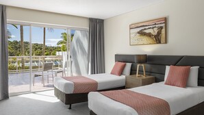 Quarto de hotel com duas camas, uma varanda e vista para a praia, e um quadro na parede.