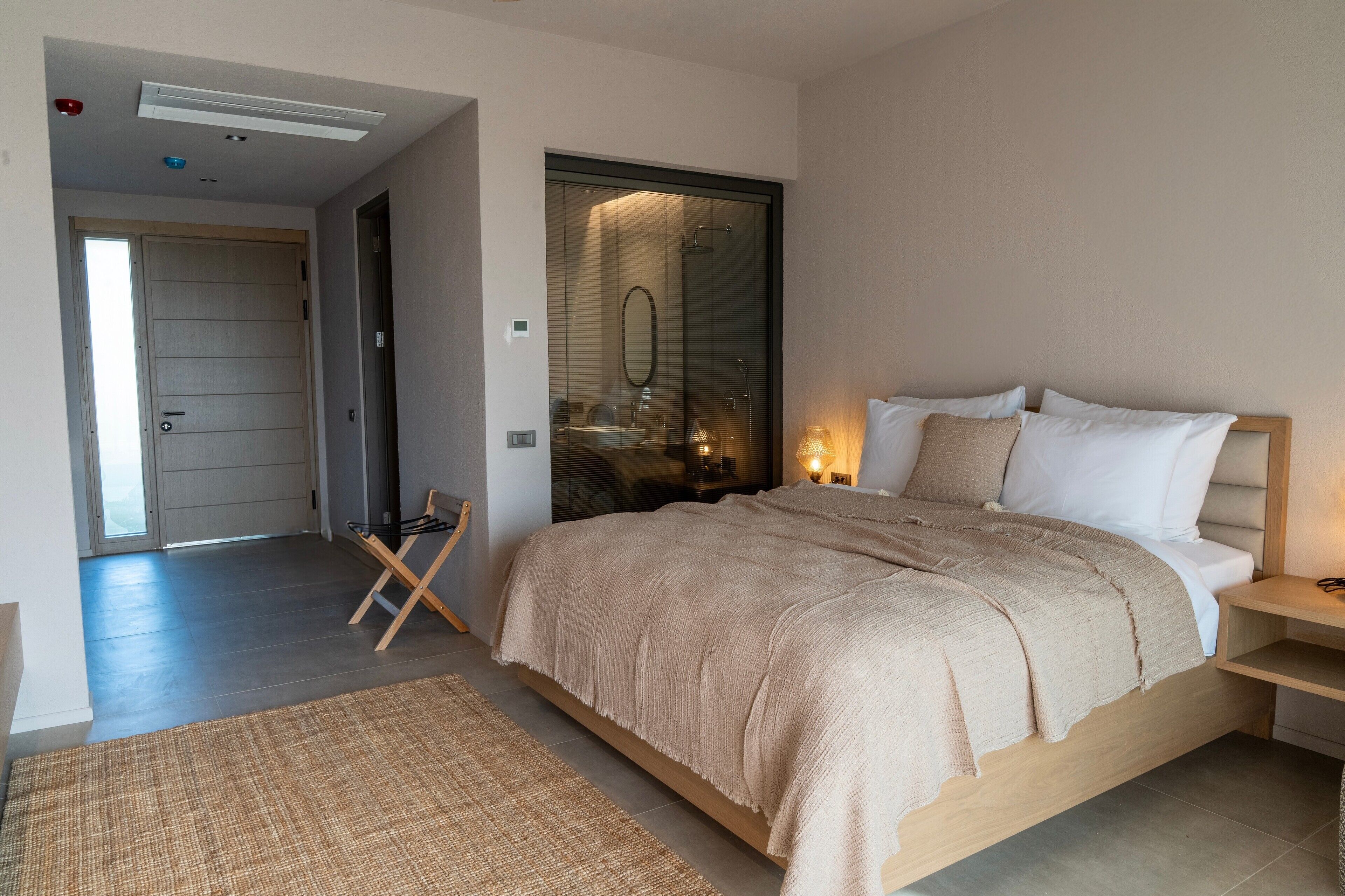 Quarto com uma cama grande, uma mesa de cabeceira de madeira e um espelho.