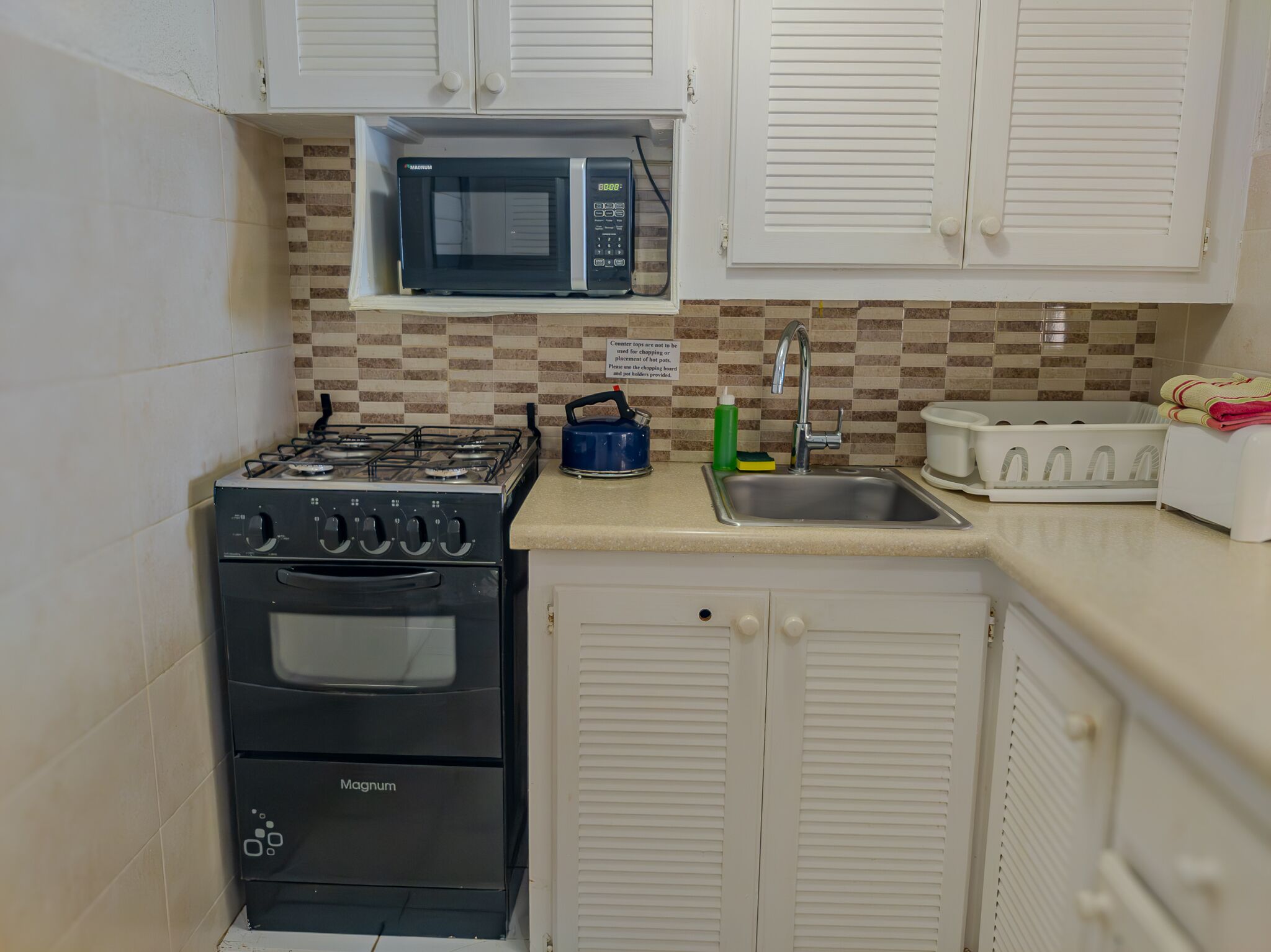 Uma cozinha compacta com fogão a gás, micro-ondas embutido, pia e uma pequena área de bancada.
