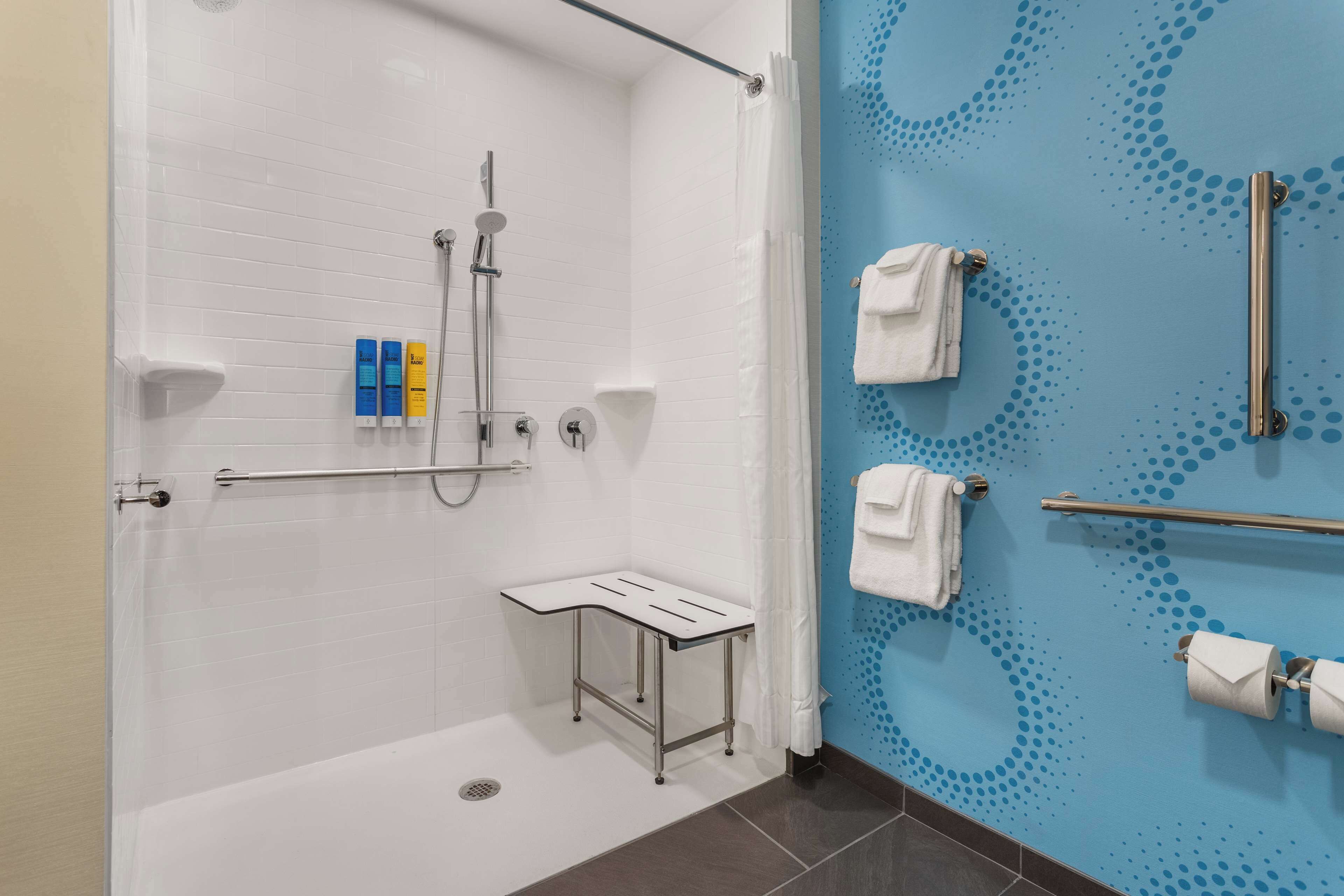 Uma casa de banho moderna com chuveiro, um pequeno lavatório e um porta-toalhas.
