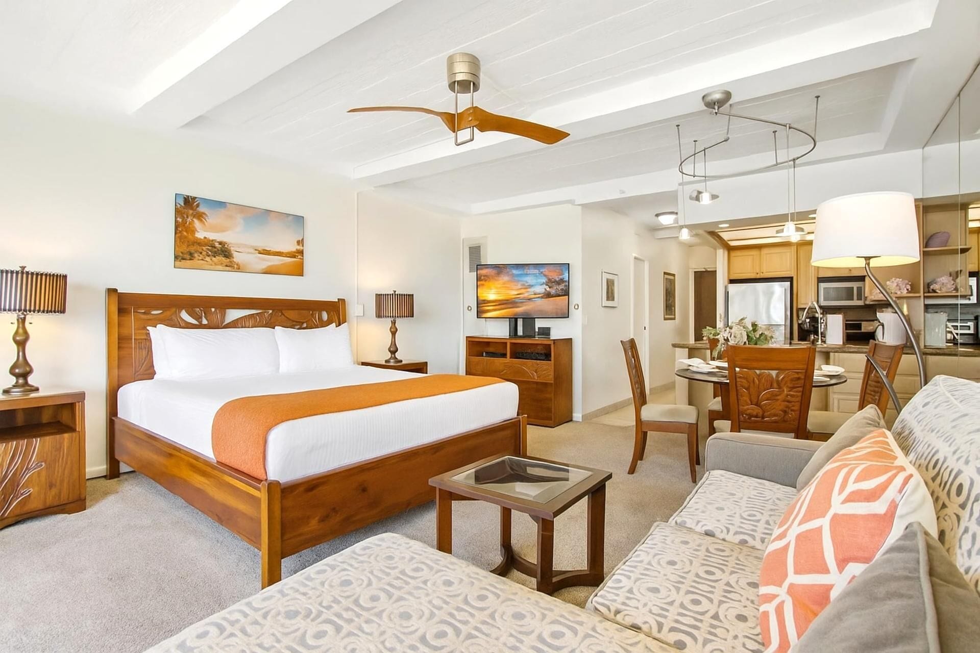 Quarto de hotel com uma cama grande, um sofá, área de jantar e cozinha.