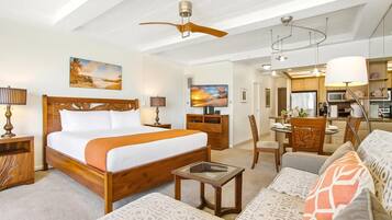 Quarto de hotel com uma cama grande, um sofá, área de jantar e cozinha.
