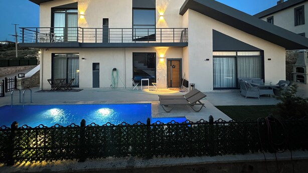Uma casa moderna de dois andares com piscina, área de estar ao ar livre e churrasqueira.