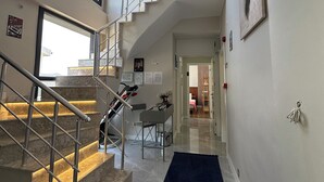 Interior moderno com escada para um segundo andar, uma escrivaninha com cadeira e um tapete azul.