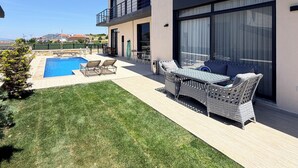 Uma casa moderna de dois andares com piscina, mobiliário de exterior e vista para a paisagem.