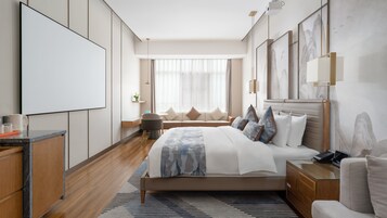 Quarto de hotel moderno com uma cama grande, uma mesa de escritório e um espaço para sentar.