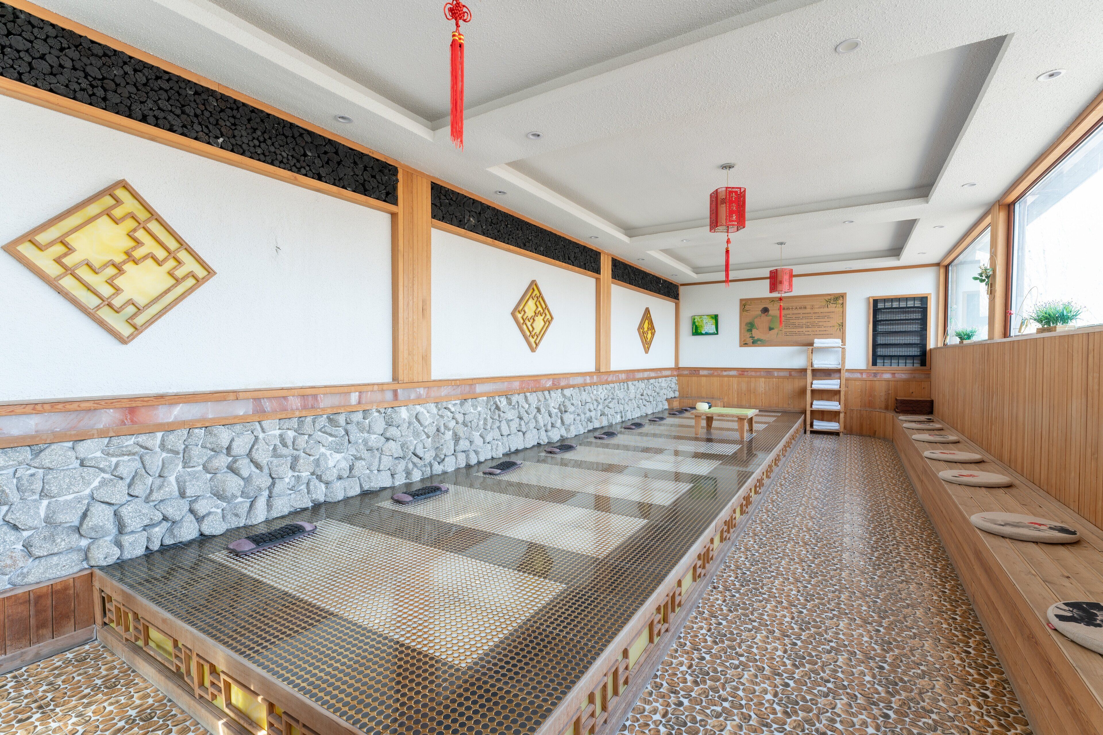 Uma onsen japonesa tradicional com paredes de pedra, bancos de madeira e piso ladrilhado.