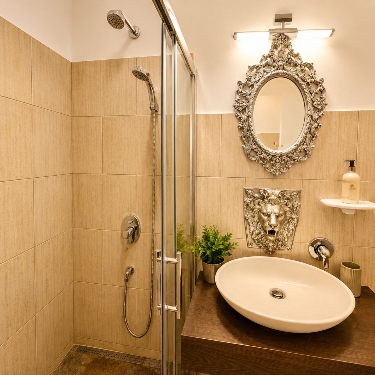 Casa de banho com chuveiro em cabine de vidro, um espelho grande com moldura elaborada, uma pia assentada em pedestal e uma cabeça de leão decorativa na parede.