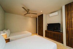Quarto de hotel moderno com cama, televisão, ventoinha no teto e ar condicionado.