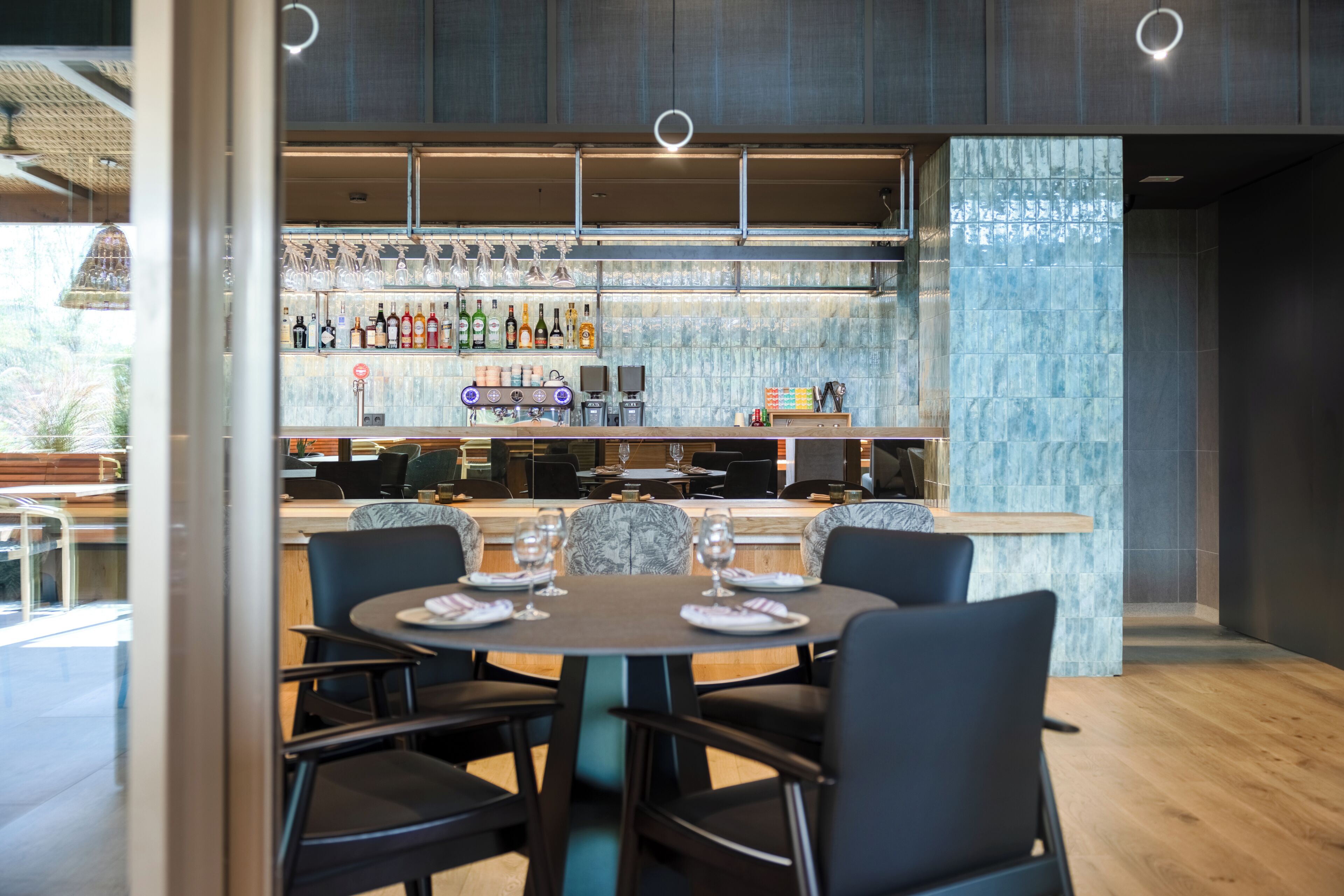 Um restaurante moderno com área de bar, várias opções de assento e vista para o exterior.