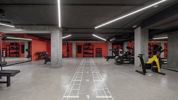 Academia com equipamentos de ginástica, um espelho e chão demarcado com números.