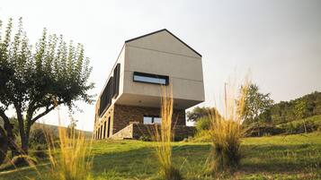 Um edifício moderno com telhado plano, base de pedra e uma grande janela.