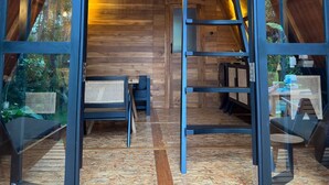Interior moderno com detalhes em madeira, teto estilo loft, mesa central em madeira e escada para o andar superior.