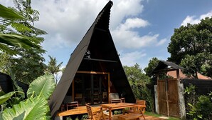 Um edifício moderno com formato triangular, um deque de madeira e área externa com assentos.
