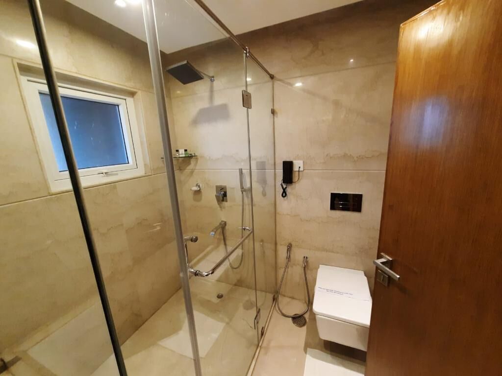 Um banheiro moderno com box de vidro, vaso sanitário e janela.