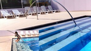 Piscina com água azul cristalina, deck revestido em azulejo e cadeiras de descanso brancas.
