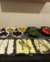 Buffet com diversos alimentos, incluindo azeitonas, queijo e legumes.
