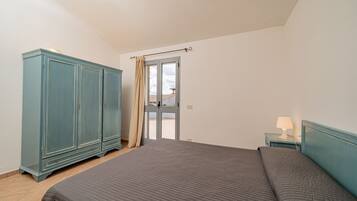 Quarto com cama, guarda-roupa e mesa de cabeceira com abajur.