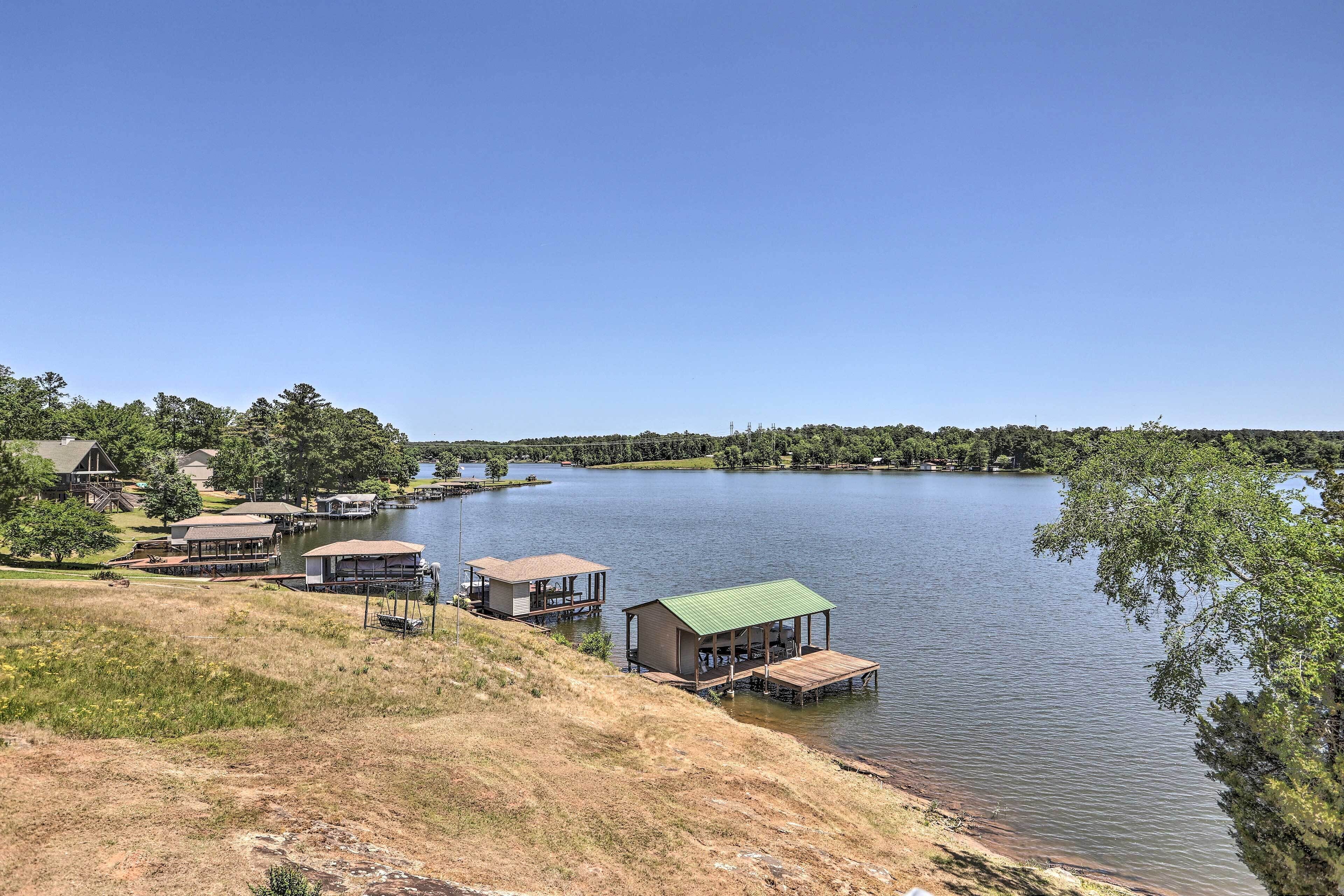 Uma propriedade à beira do lago com vários barcos atracados, uma área gramada e uma vista desobstruída do lago.