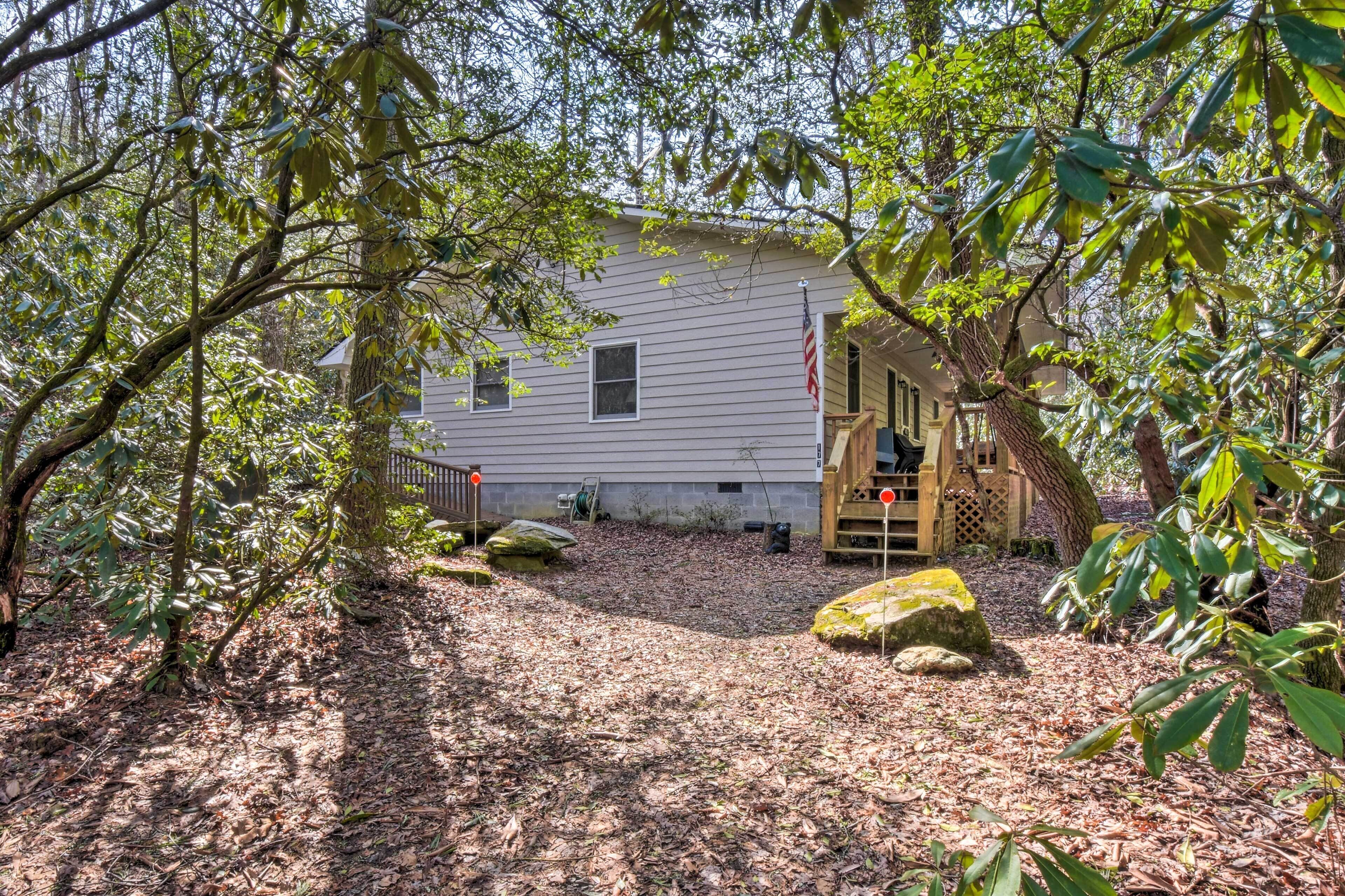 Uma casa com varanda, cercada por árvores e área arborizada.