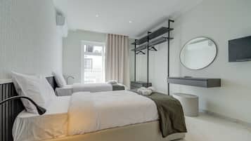 Quarto de hotel moderno com uma cama grande, mesa de cabeceira, espelho e vista exterior.