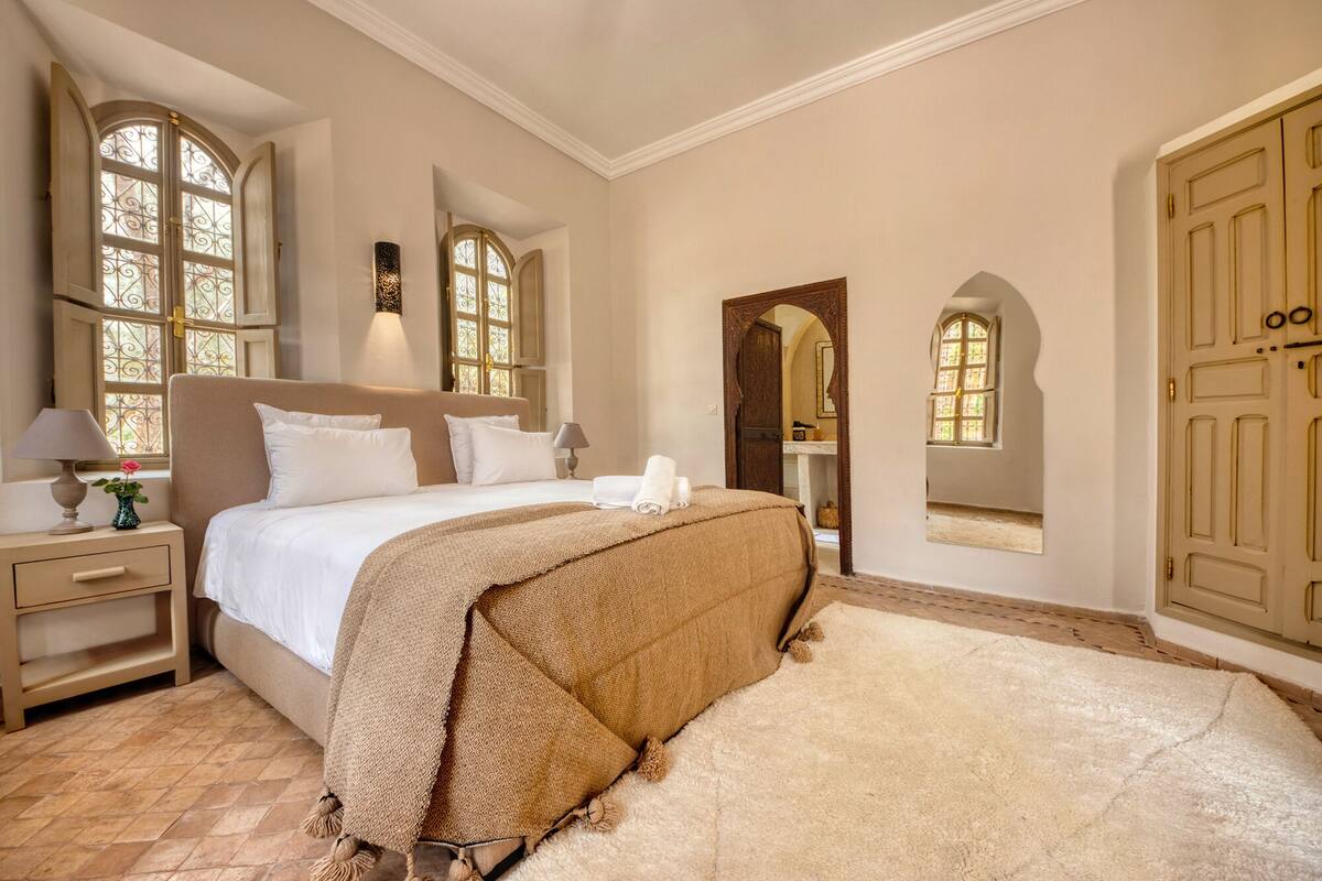 Quarto com uma cama grande, duas mesas de cabeceira, um espelho e um guarda-roupa.